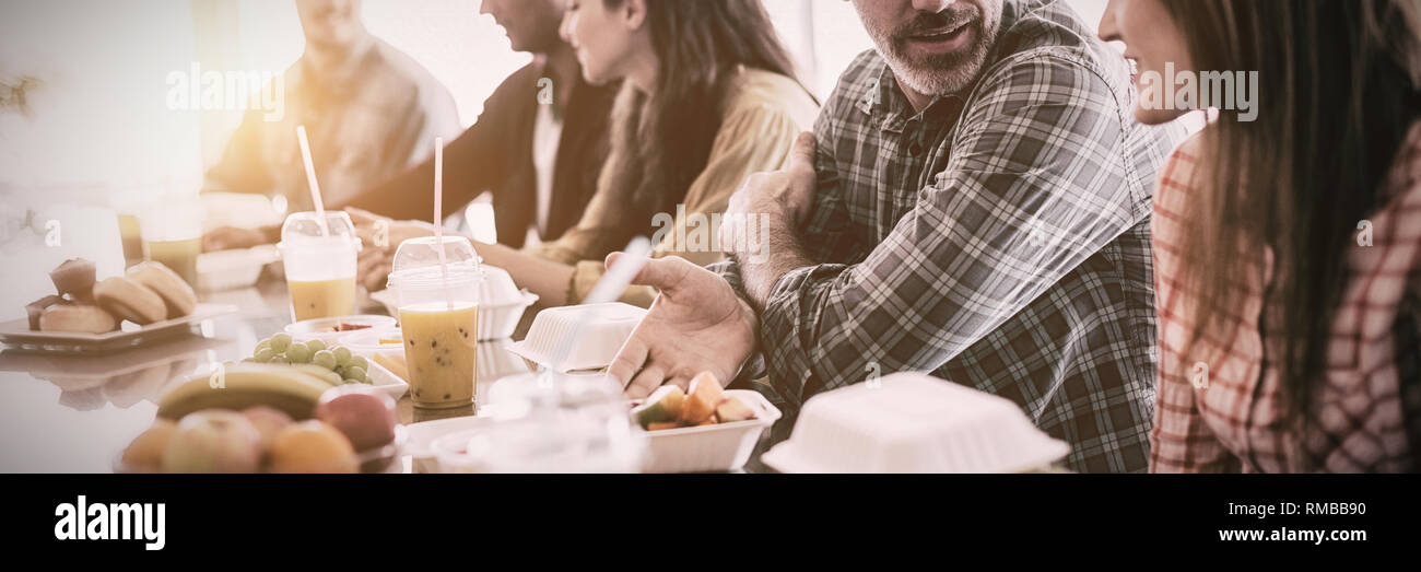 Creative business team discussing while having meal Stock Photo - Alamy