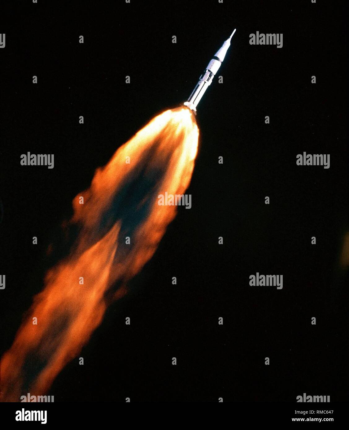 A Saturn rocket booster with a spacecraft after the lift-off with a ...