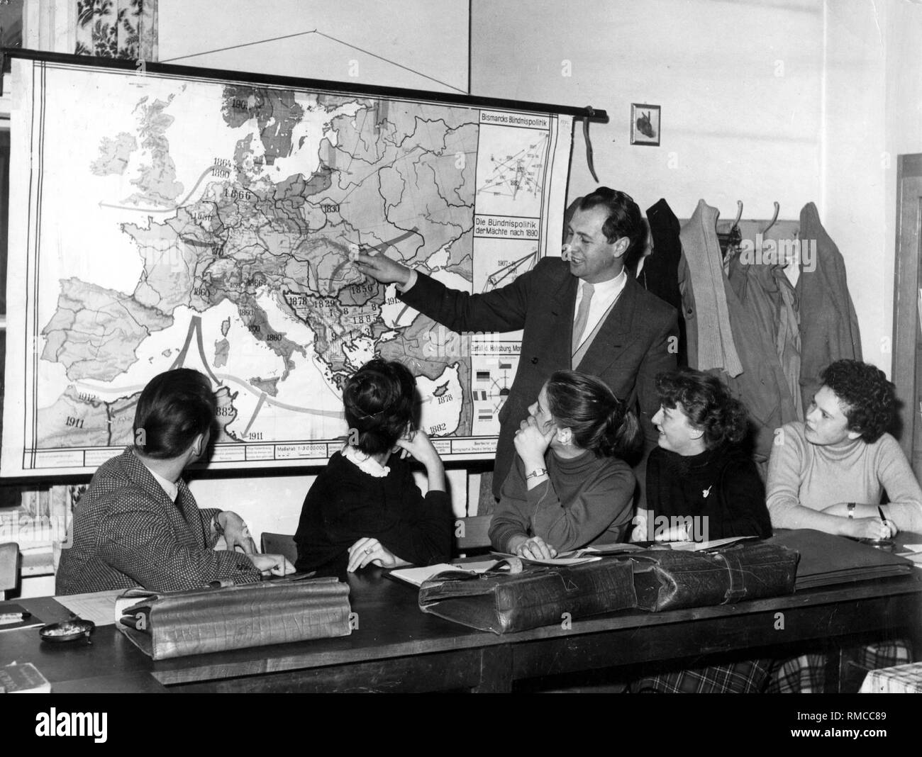 The teacher shows something to his students on a large map during a ...