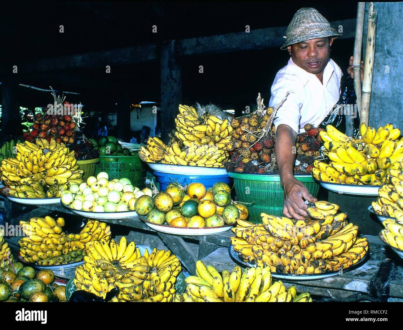 Fruit seller at his stand with bananas and citrus fruits. (undated ...