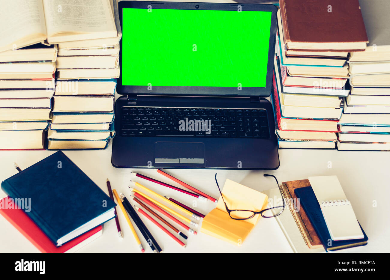 Green screen laptop, stack of books, notebooks and pencils on white ...