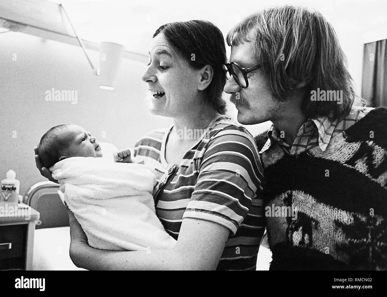 Father and mother look at their baby, a few days old, at the maternity ...