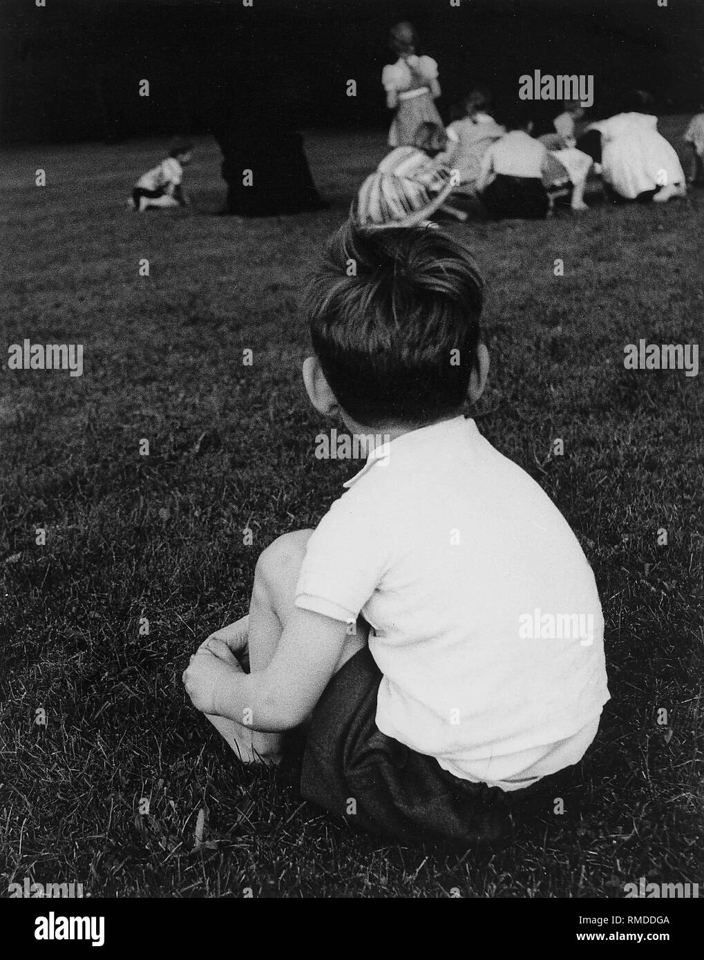 A little boy watches other kids playing Stock Photo - Alamy