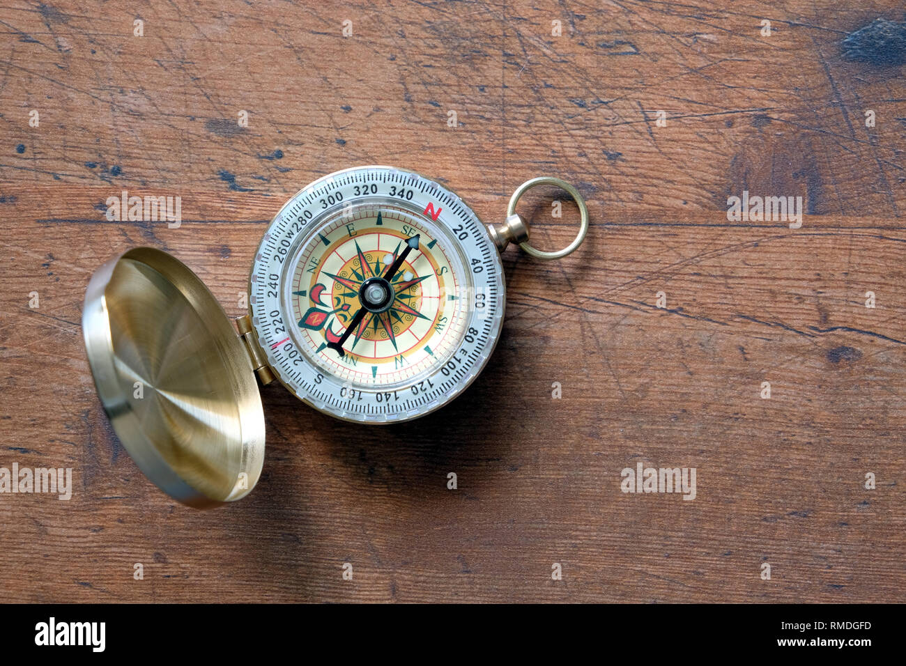Old compass in opened brass case on vintage brown wooden background ...