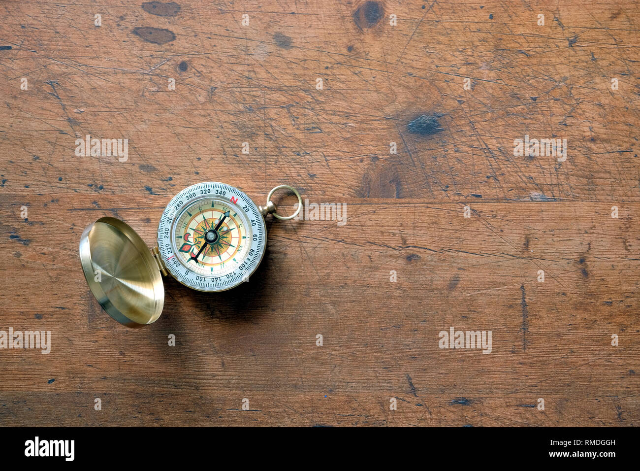 Old compass in opened brass case on vintage brown wooden background ...