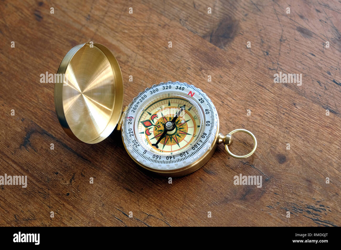 Old compass in opened brass case on vintage brown wooden background ...