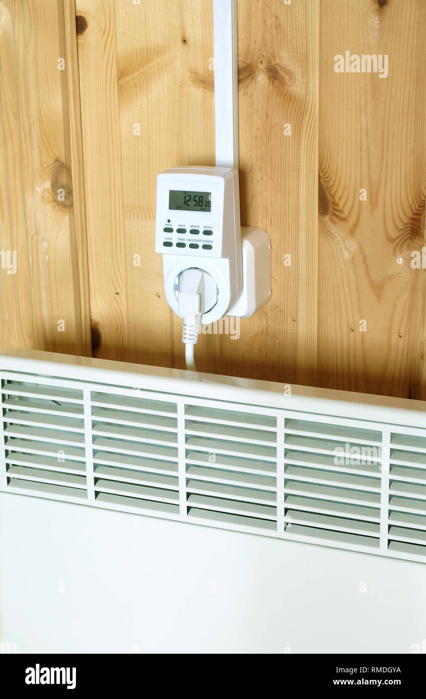 Working white electric convector heater plugged to timer power socket ...