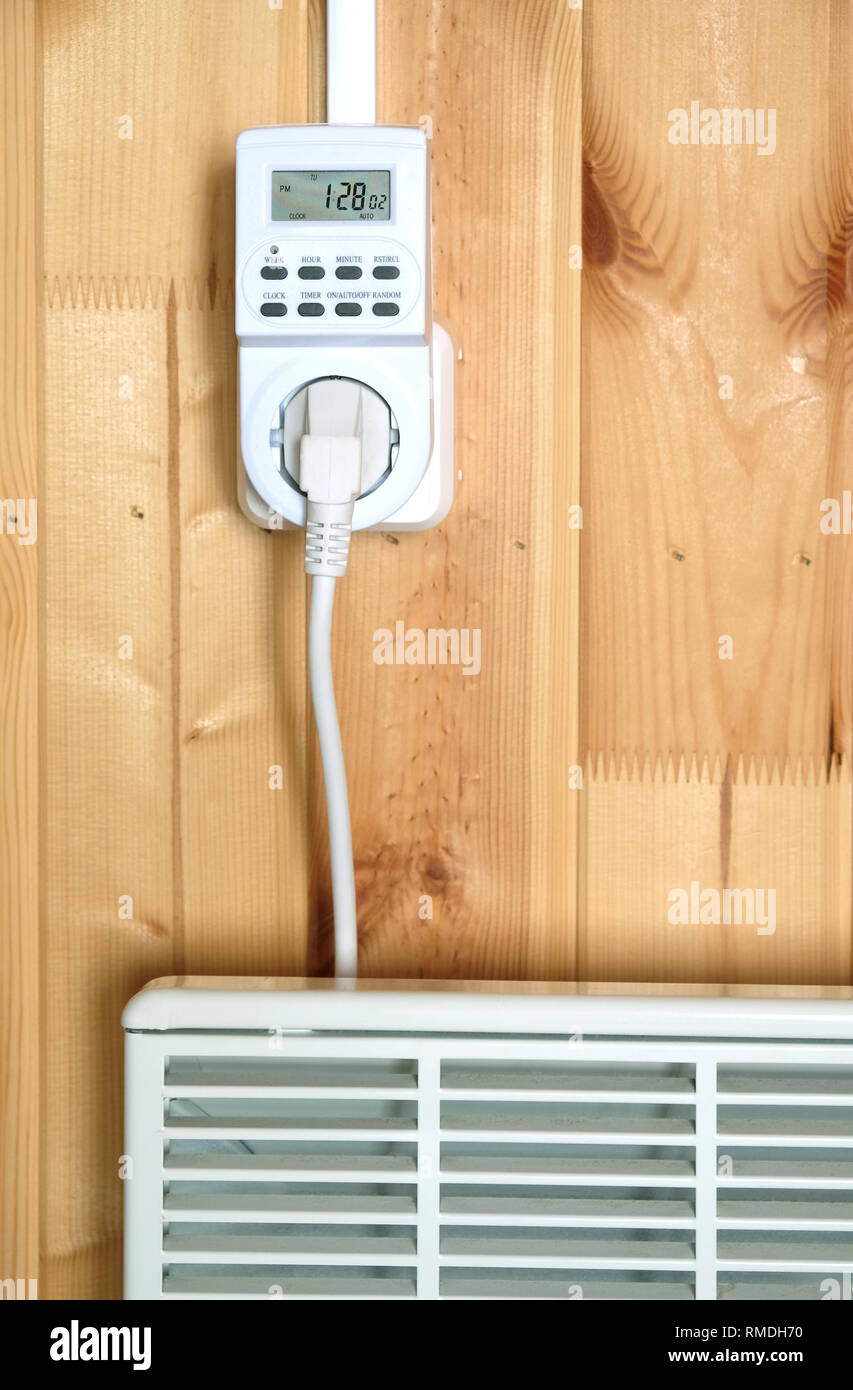 Working white electric convector heater plugged to timer power socket ...