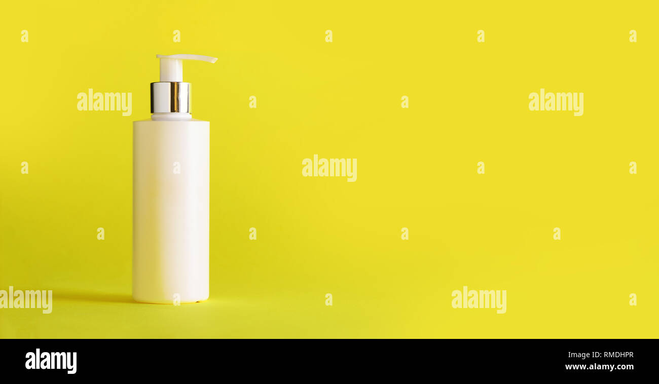 White bottle of moisturizing lotion on yellow background with copy ...