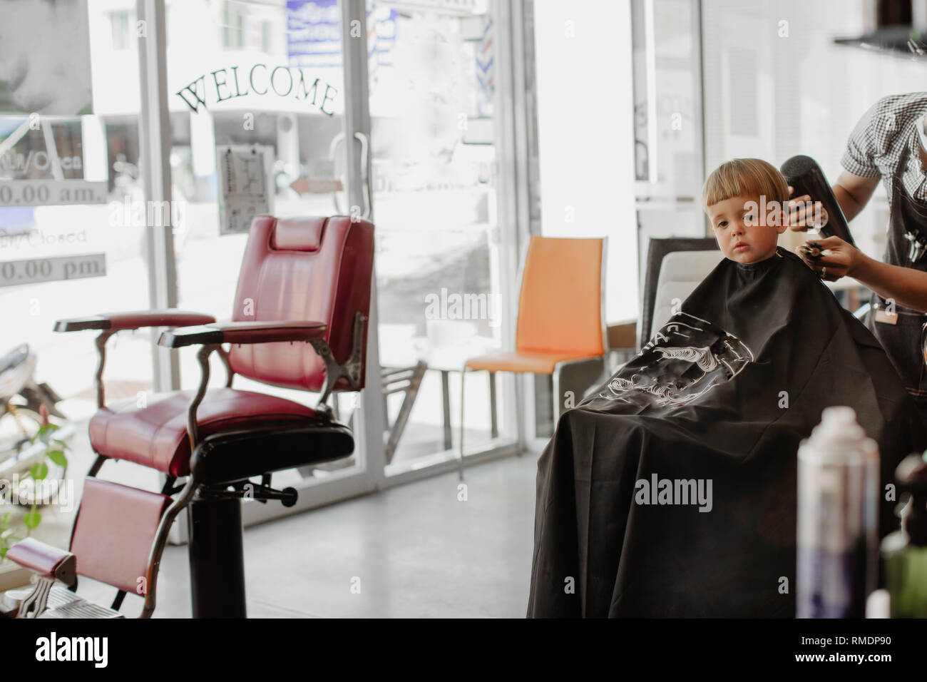 Barber giving haircut to adorable boy Stock Photo - Alamy