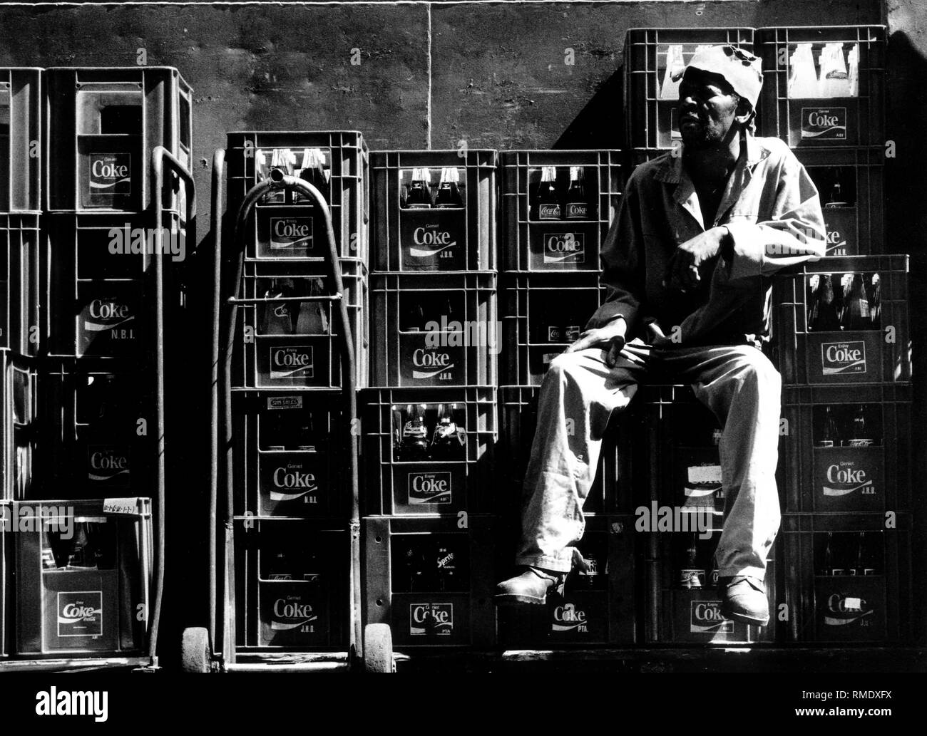 A colored worker rests on a pile of Coca-Cola boxes Stock Photo - Alamy