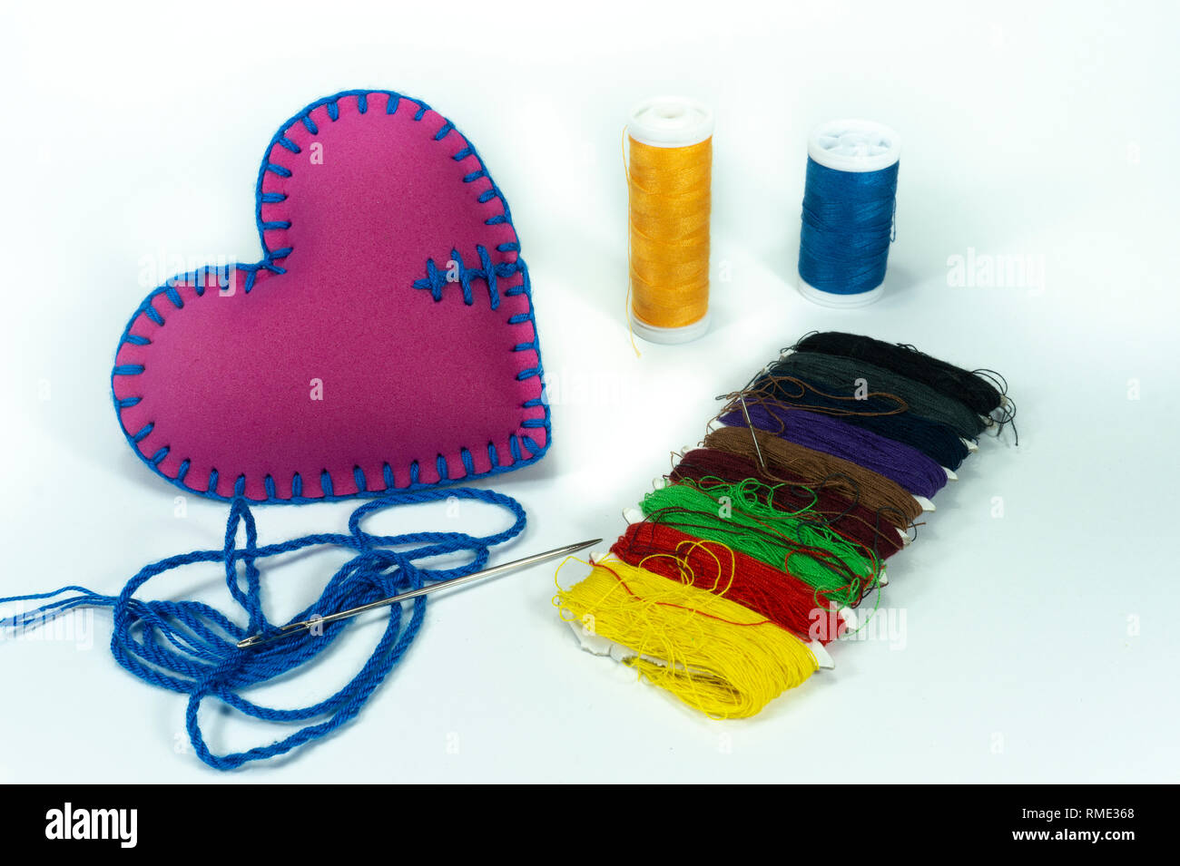Hand stitched textile heart and colored sewing threads isolated on ...