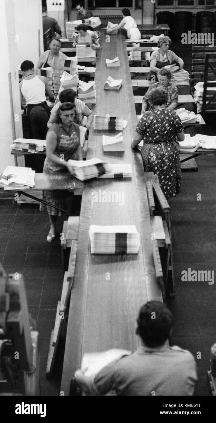 Workers place the newspaper issues ready for delivery on an assembly ...