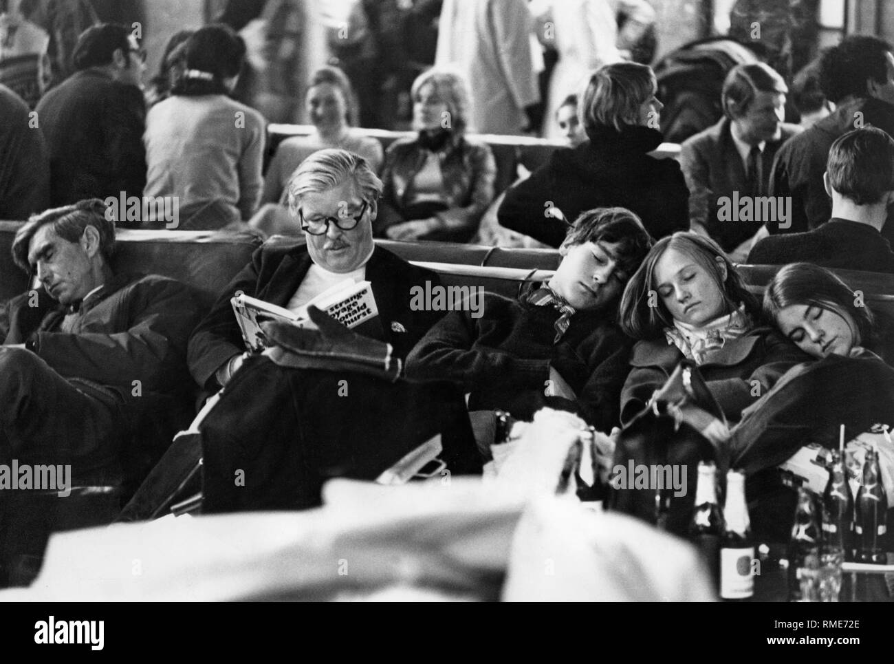 Passengers try to bridge the long waiting times due to the weather by ...