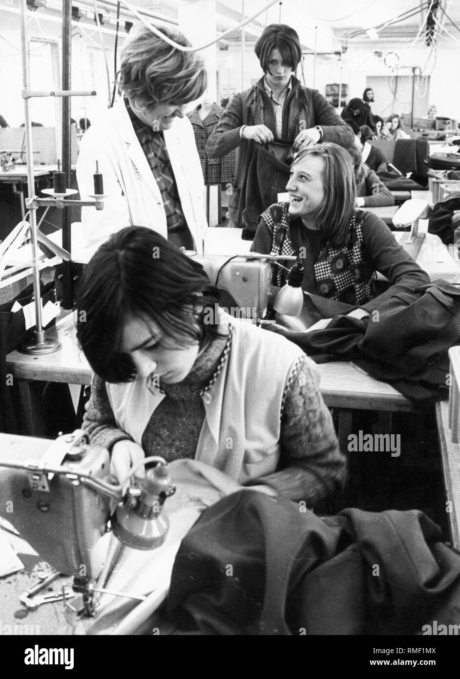 Young women working on sewing machines, and a female supervisor in a ...