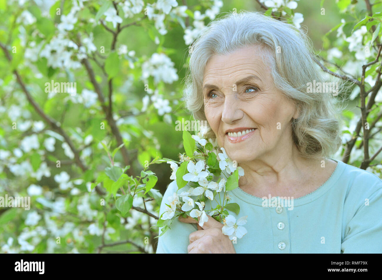 Beautiful senior woman posing near blooming tree Stock Photo - Alamy