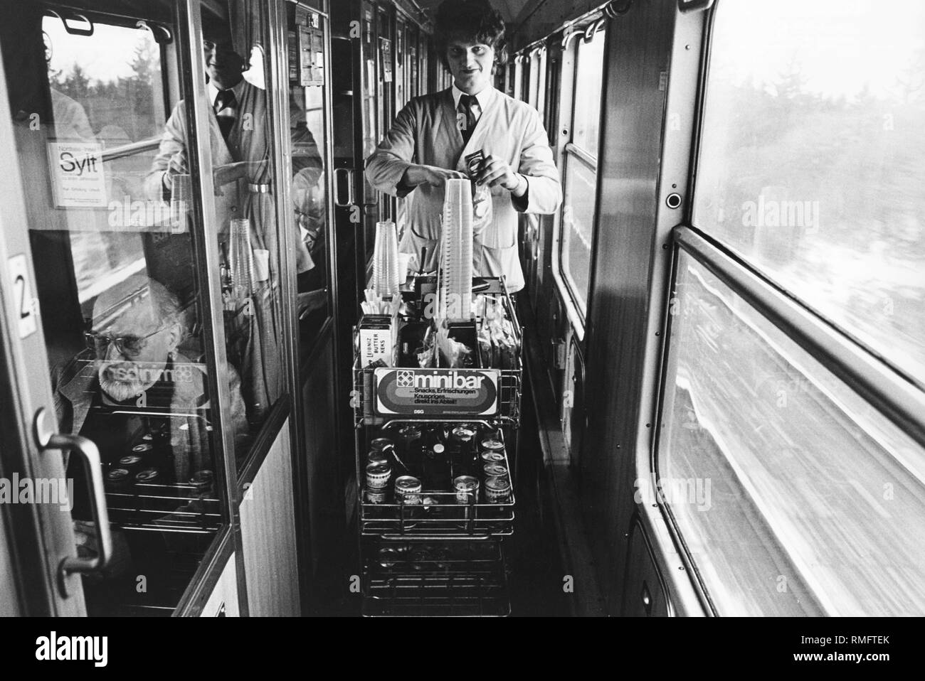 A railway employee sells snacks from the mini bar on wheels on the ...