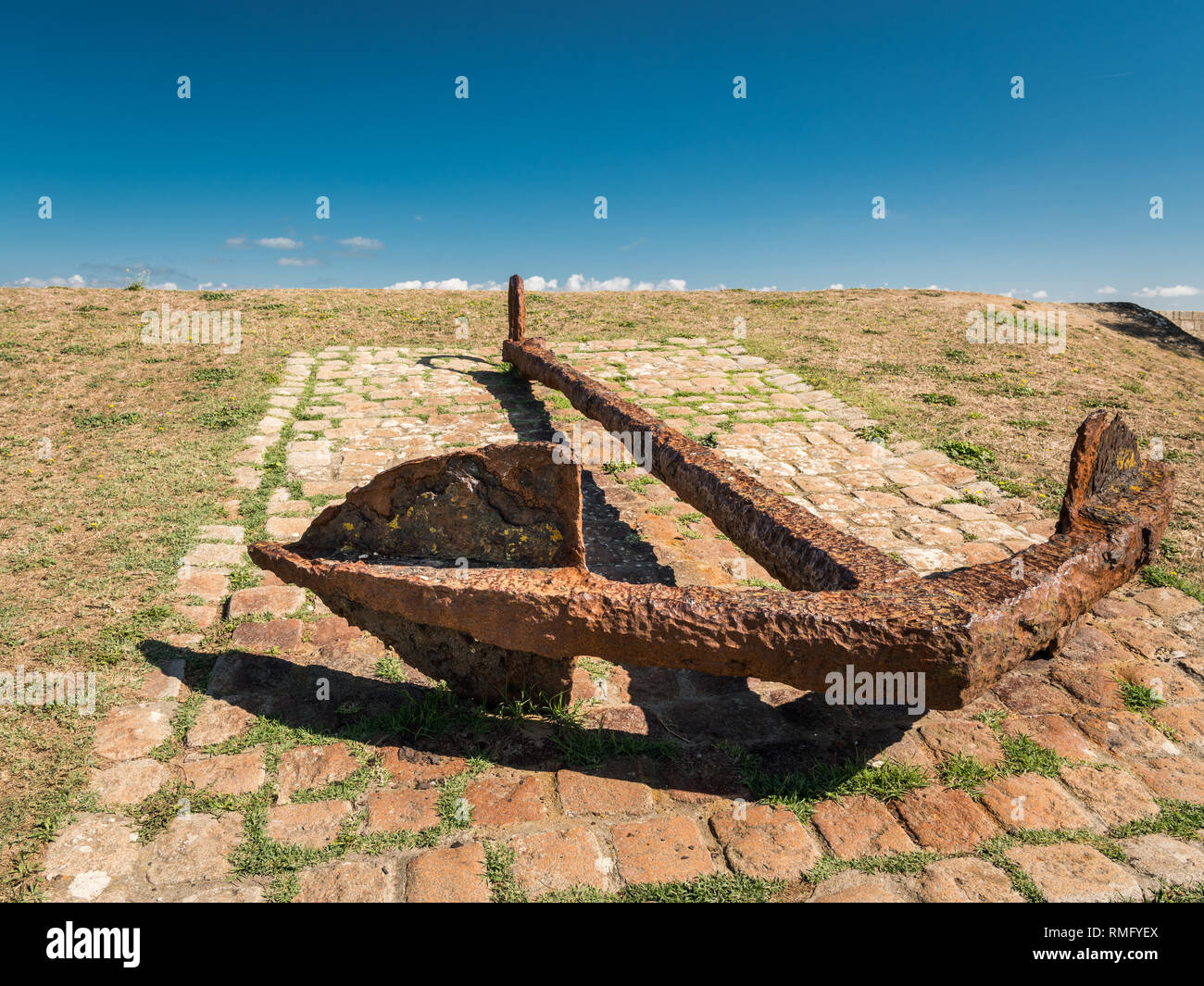 A big rusty anchor lying on the ground, blue sky in summer (France ...