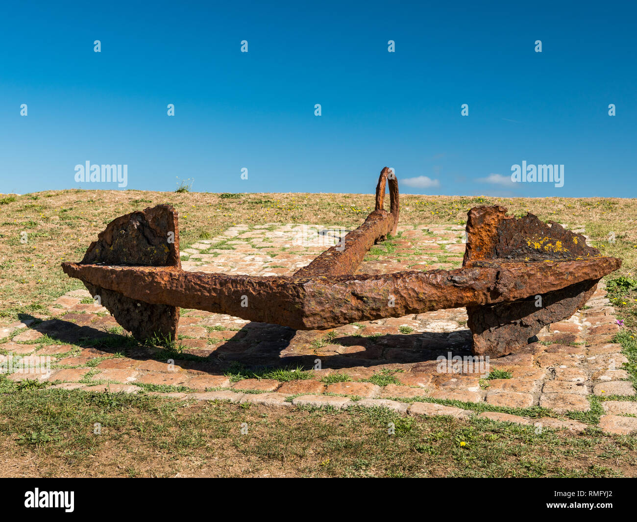 A big rusty anchor lying on the ground, blue sky in summer (France ...