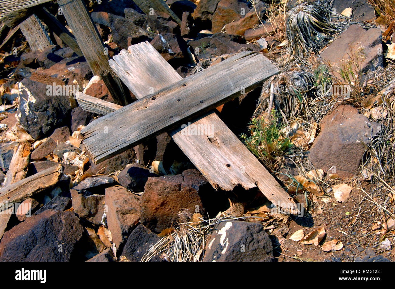 Weathered and worn cross lies broken and alone on a pile of rocks ...