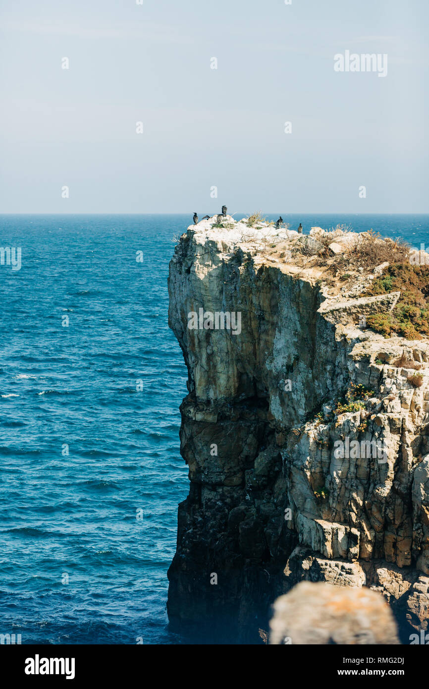 Rough cliff in blue sea Stock Photo - Alamy