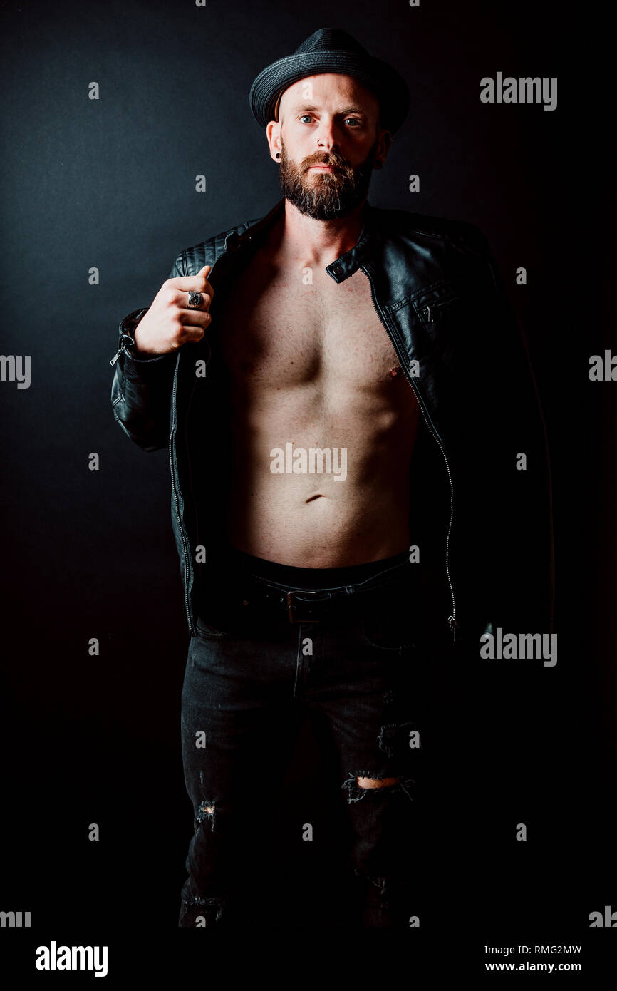 Shirtless cool hipster in hat adjusting leather jacket and looking at ...