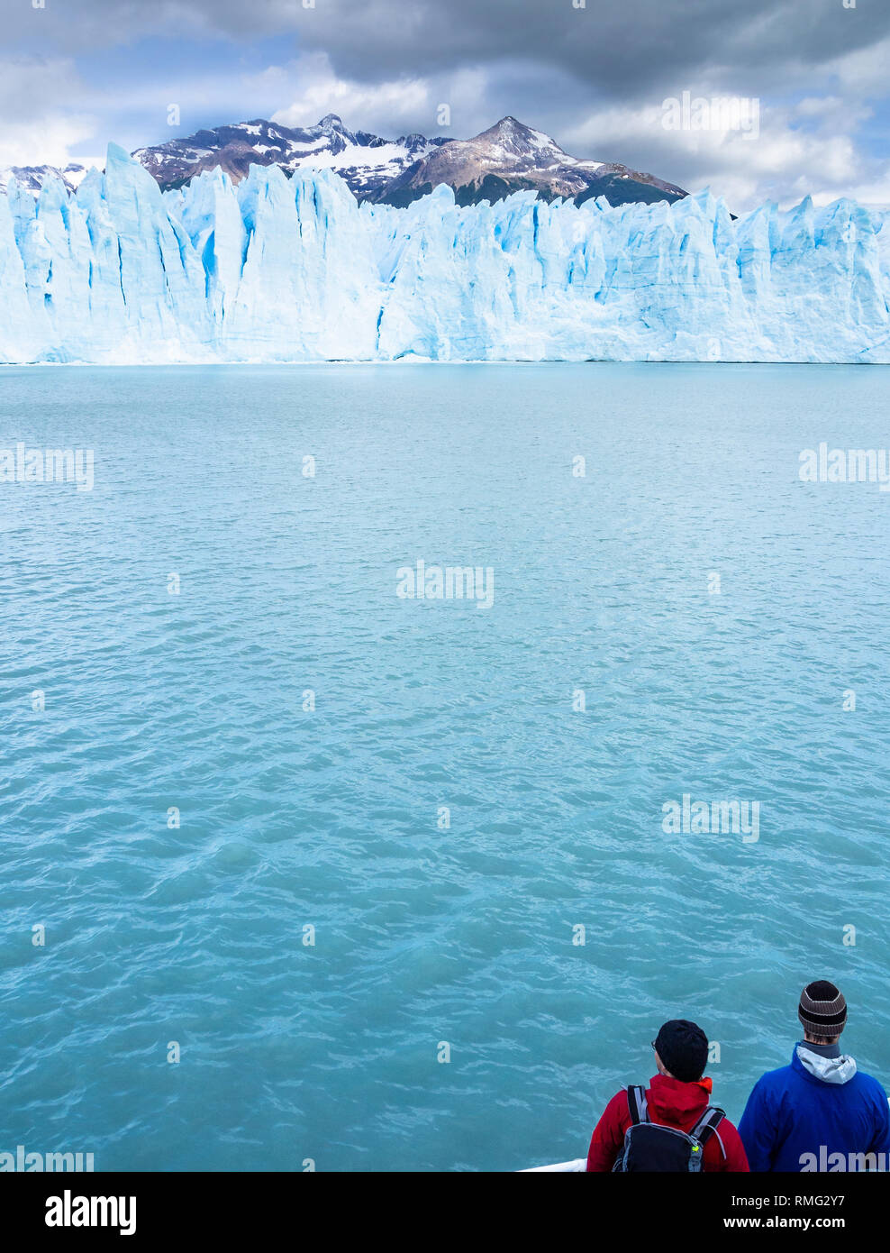 Back view of two tourists admiring calm cold sea and spectacular ice ...