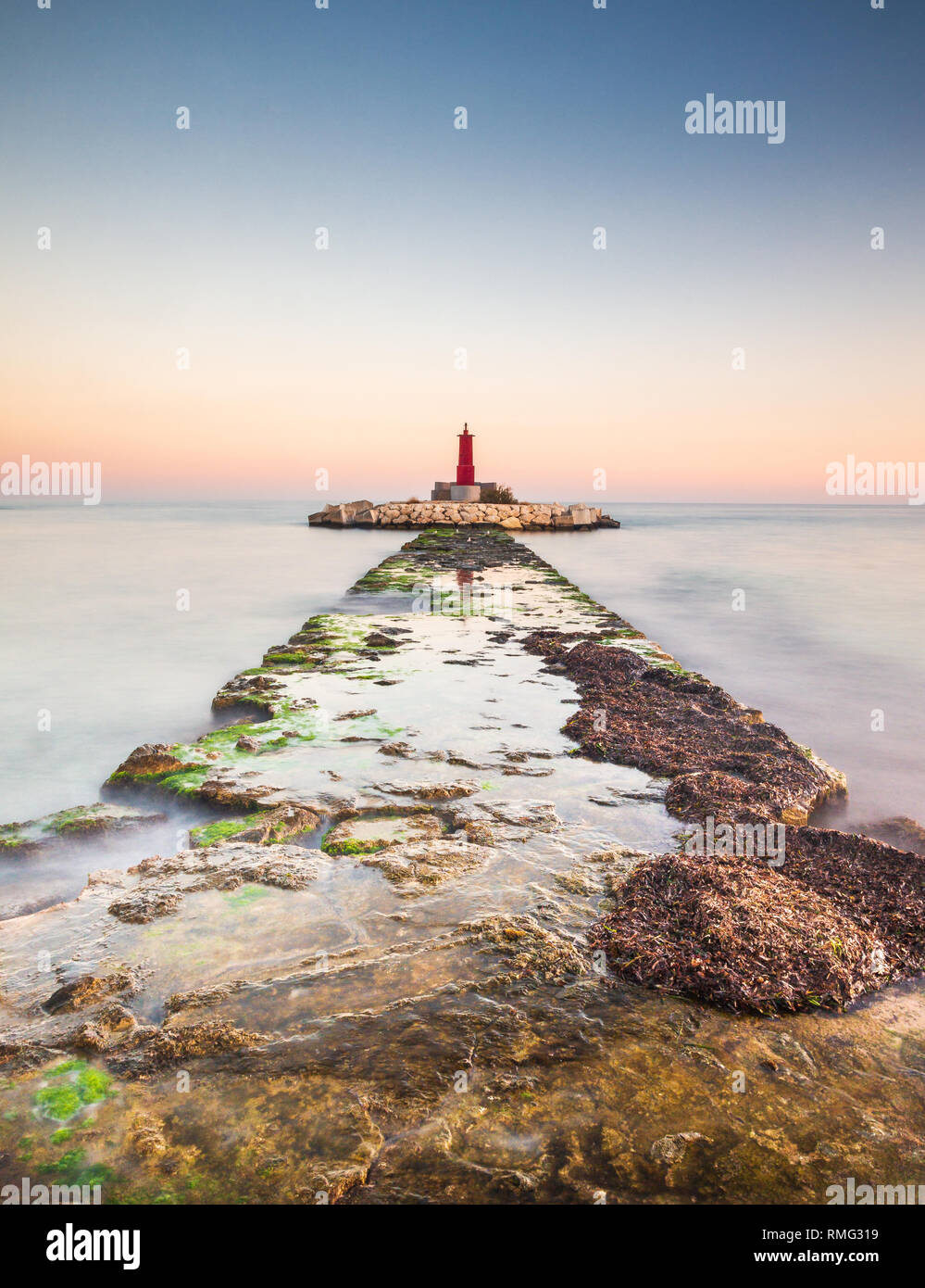 Rough path to islet with lighthouse Stock Photo - Alamy