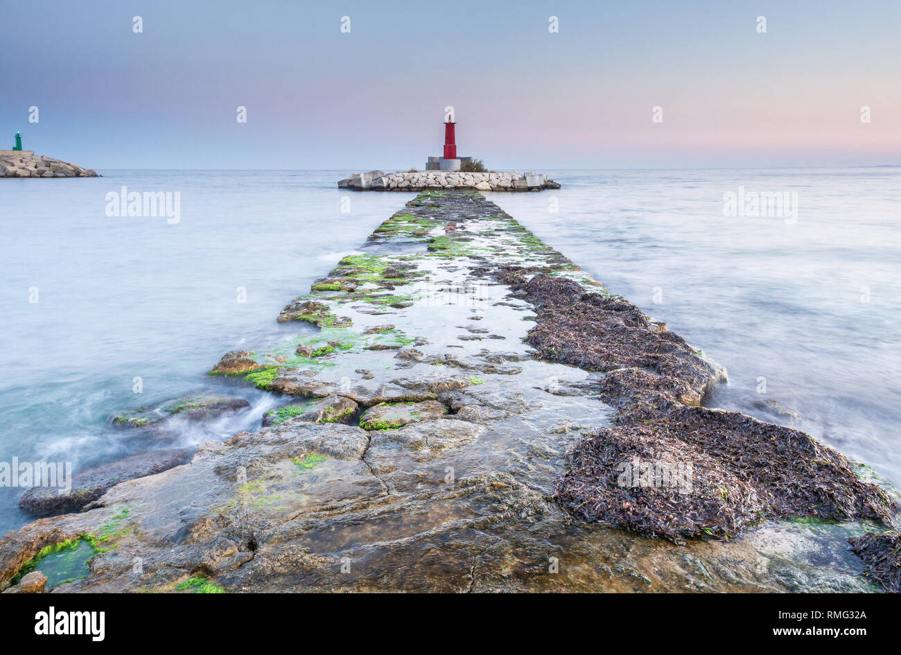 Rough path to islet with lighthouse Stock Photo - Alamy