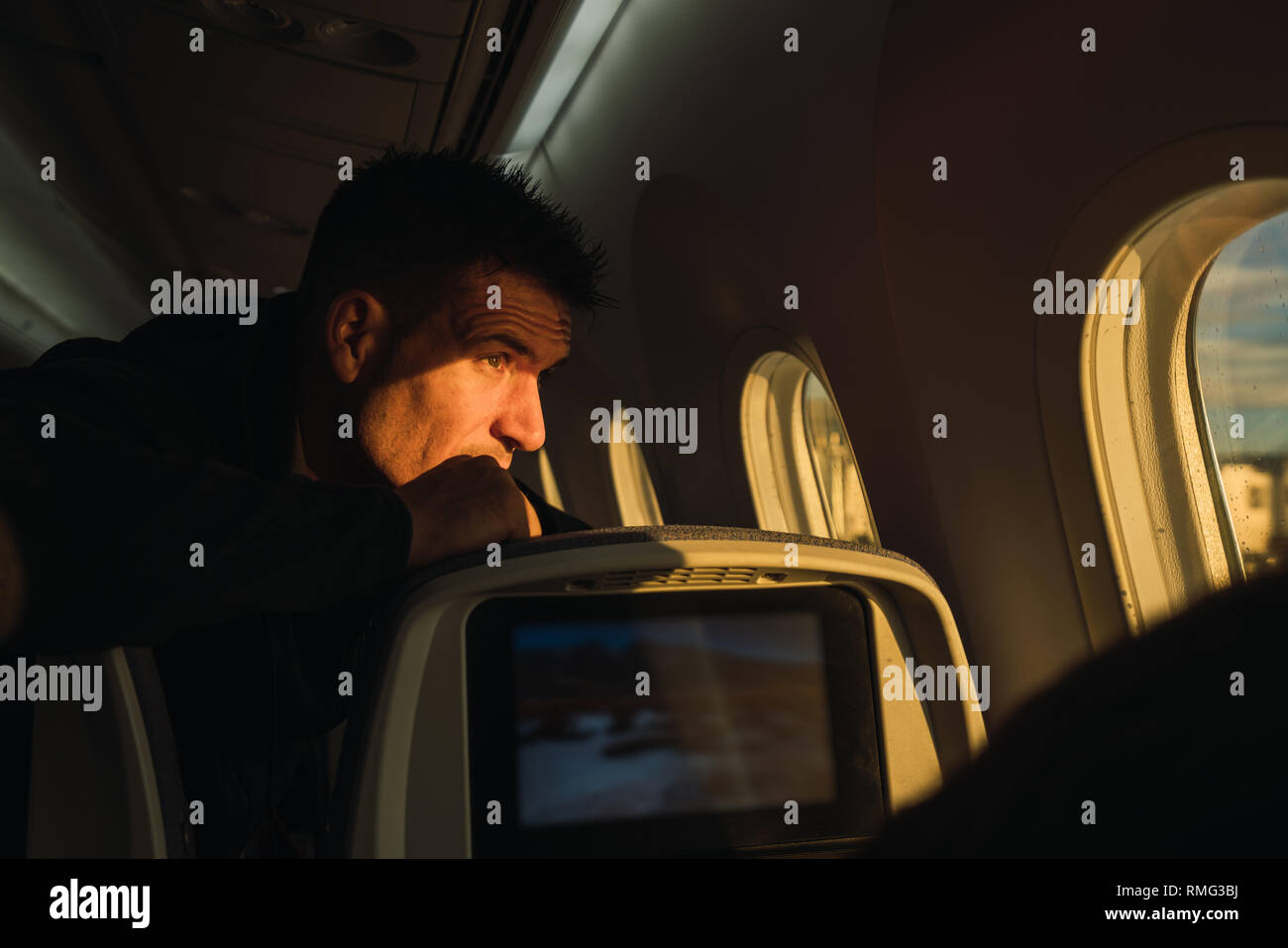 Side view of adult male looking out window of modern aircraft and ...
