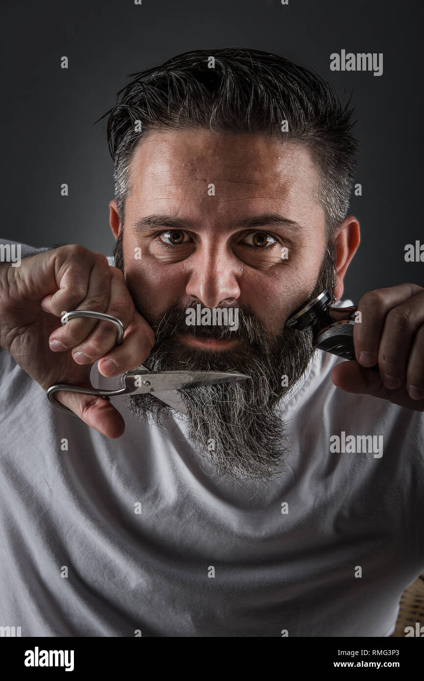 Expressive barber cutting beard Stock Photo - Alamy