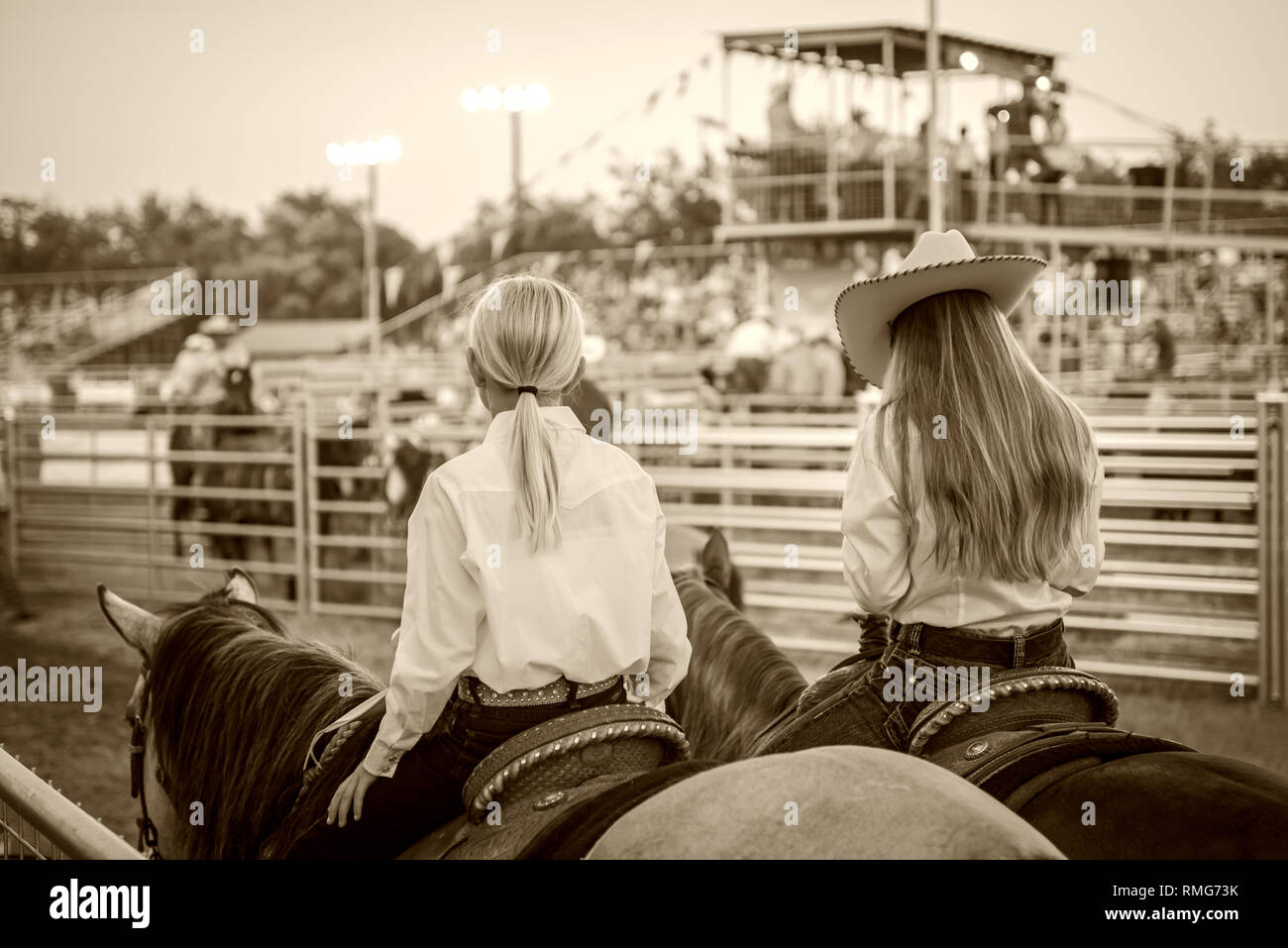 Cowgirls horseback watching rodeo event Stock Photo - Alamy