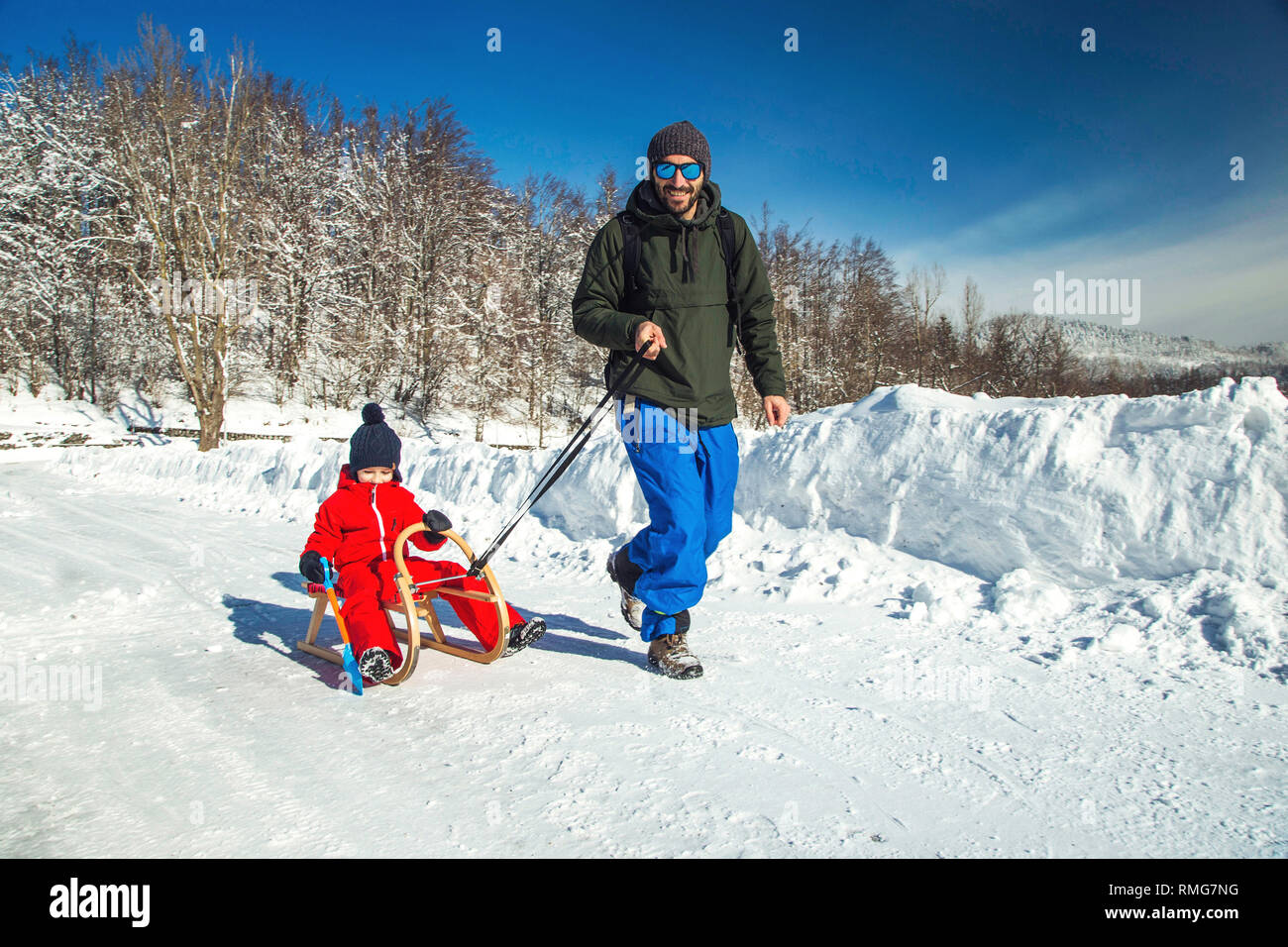 Happy father and his son enjoying sledding ride. Happy family with sled ...