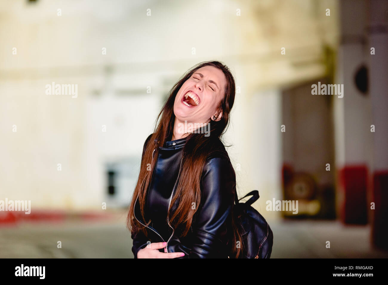 Woman surprised by a joke laughing to noisy laughter, opening her mouth ...