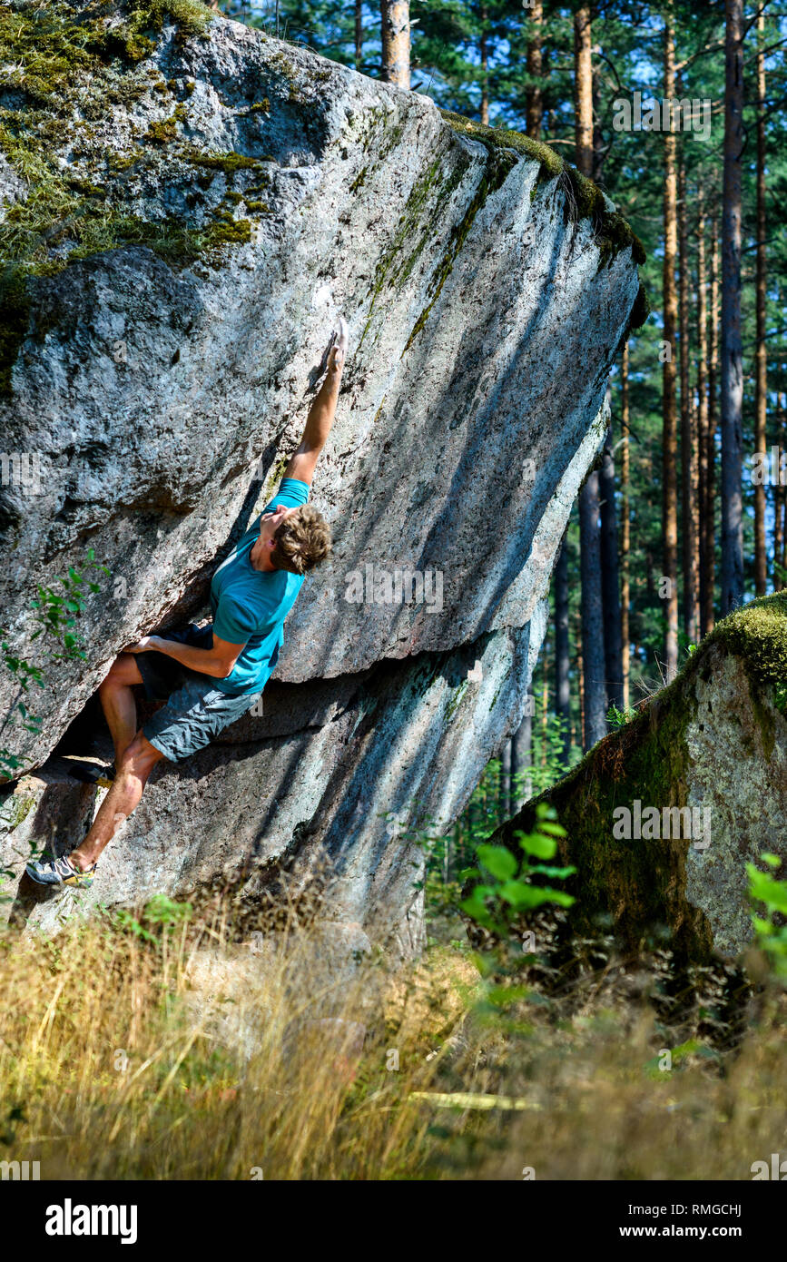Athlete climber climbing overhanging boulder rock, beautiful view of ...