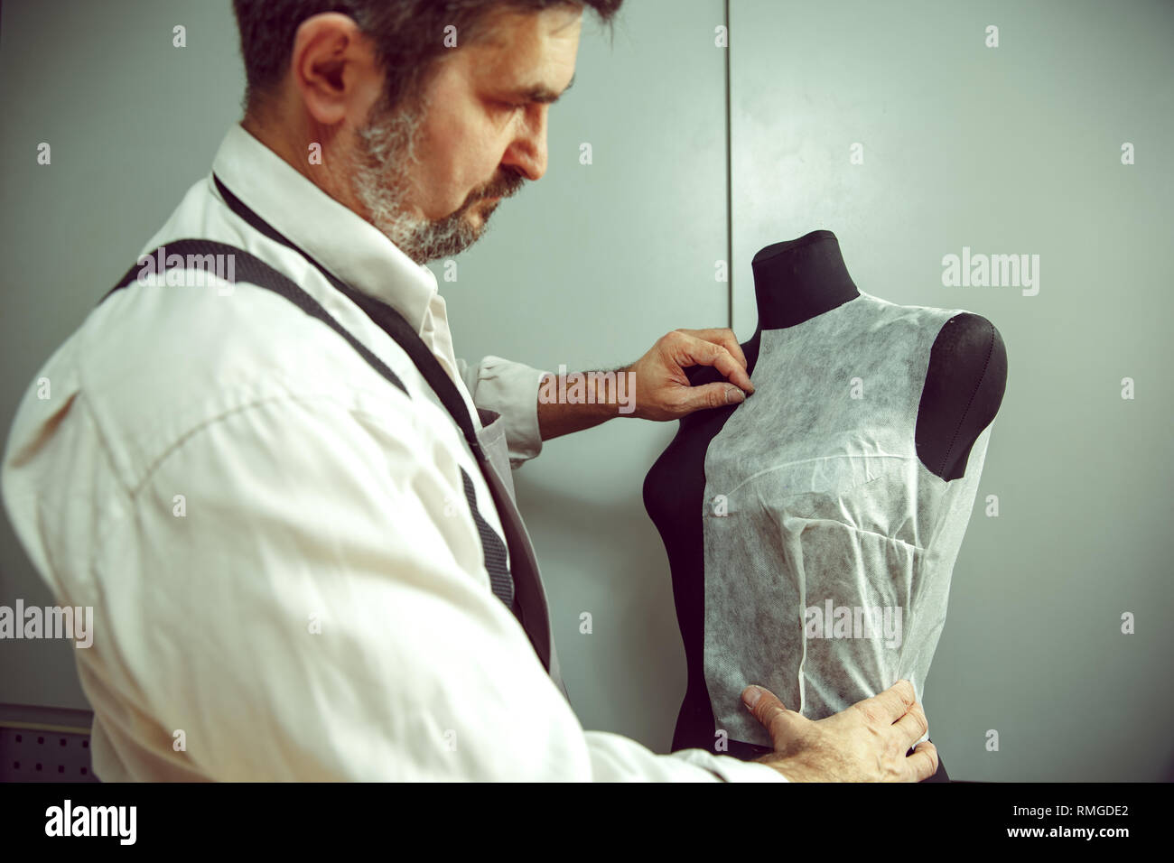 Closeup of tailors table with male hands tracing fabric making pattern ...