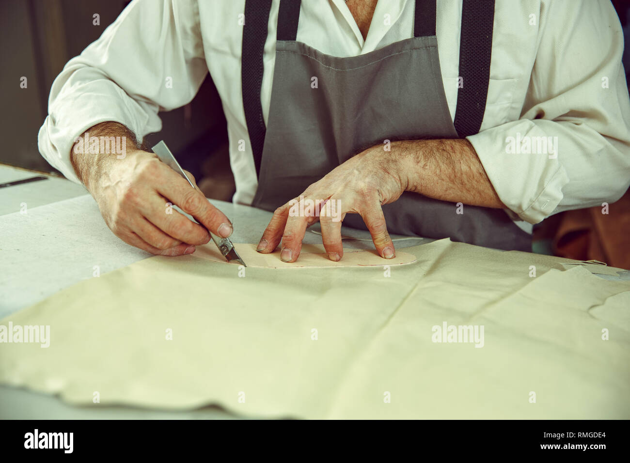 Closeup of tailors table with male hands tracing fabric making pattern ...