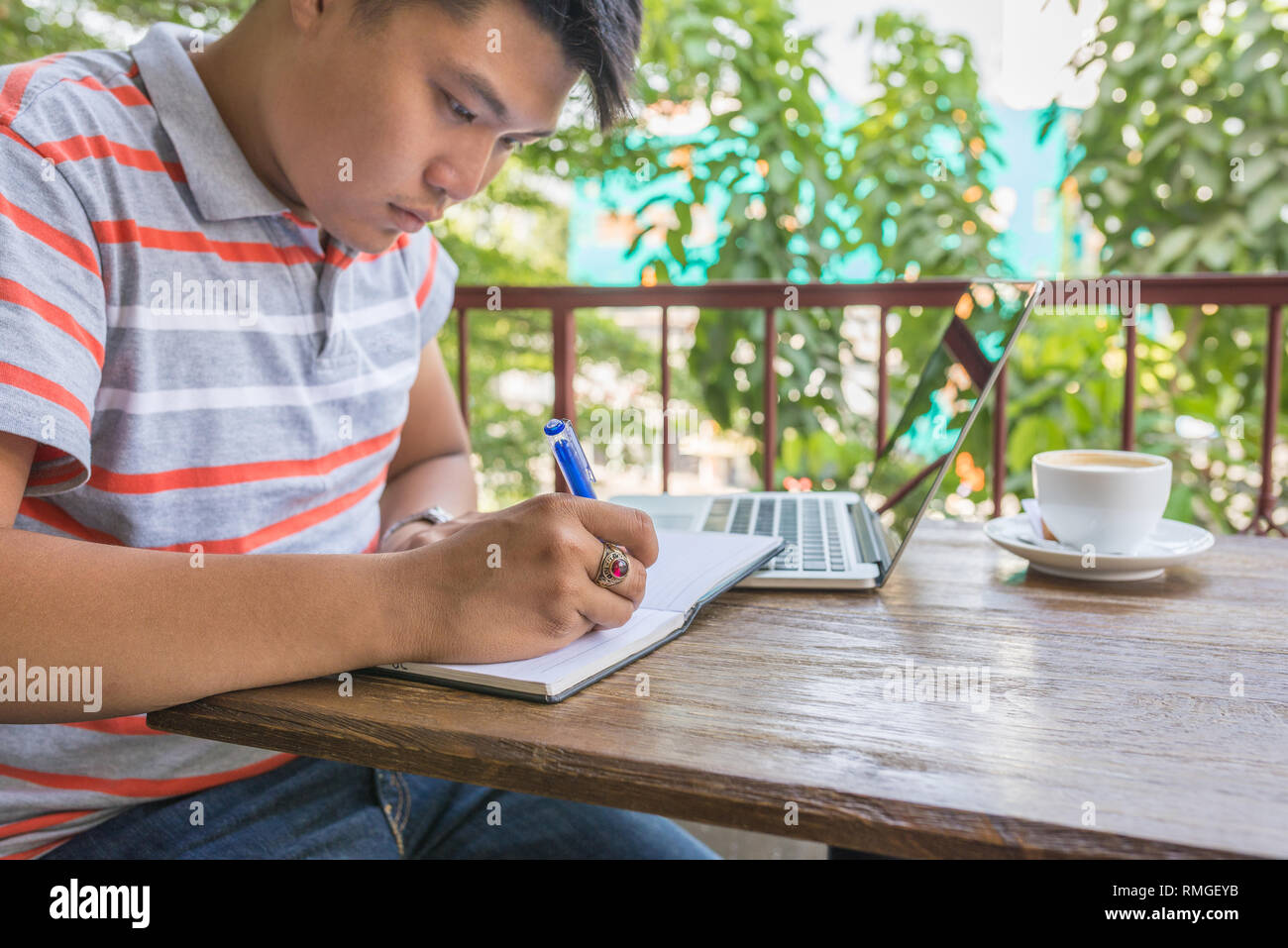 Young Asian man writing notes at cafe Stock Photo - Alamy