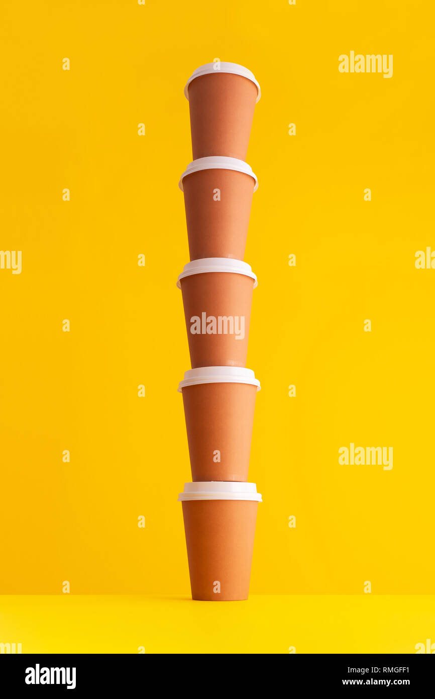 Multiple disposable coffee cups organized in a stack over yellow ...