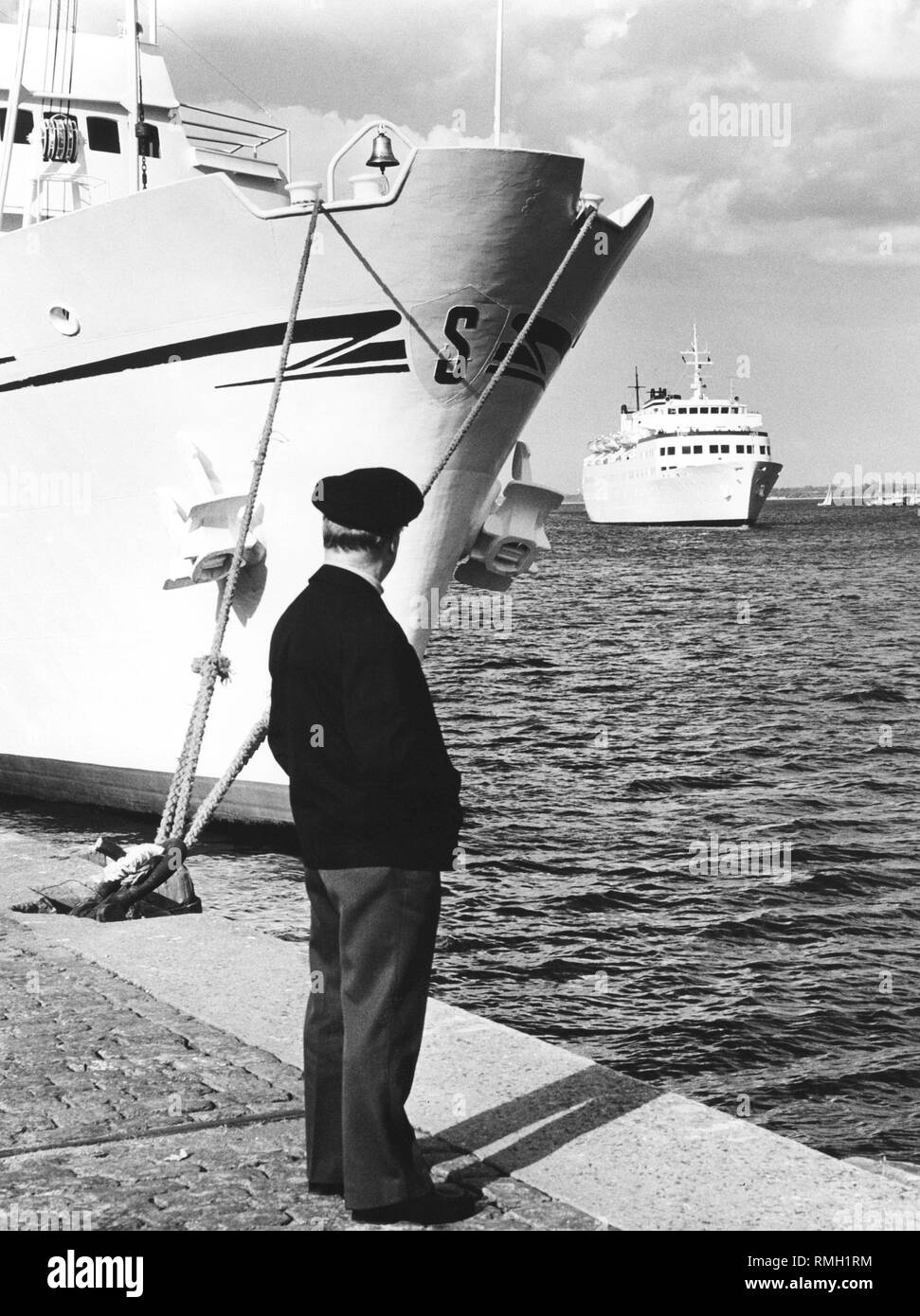 A man looks at an incoming passenger ship from the quay Stock Photo - Alamy