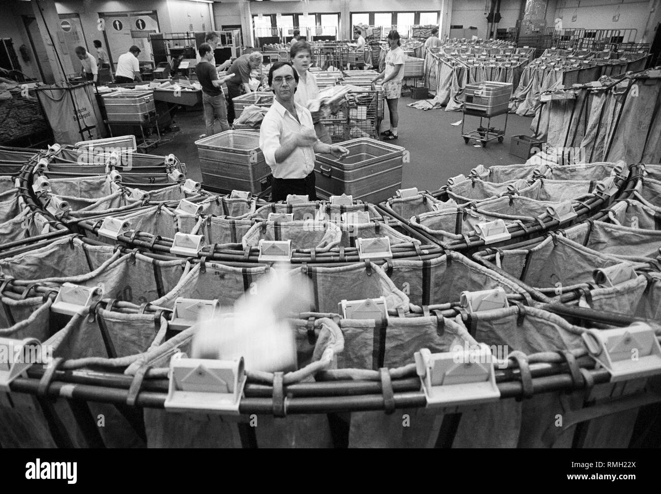 DEU , GERMANY : An employee is throwing letters into postal bags in a ...