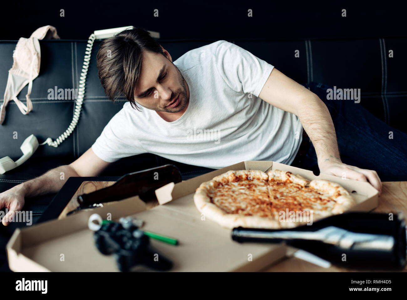drunk man looking at tasty pizza at messy home after party Stock Photo ...