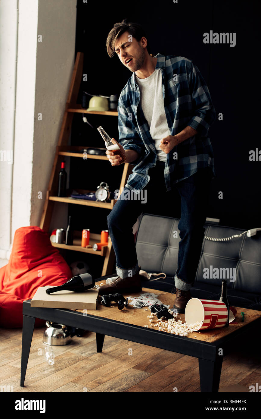 drunk man standing on coffee table and singing after party at home ...