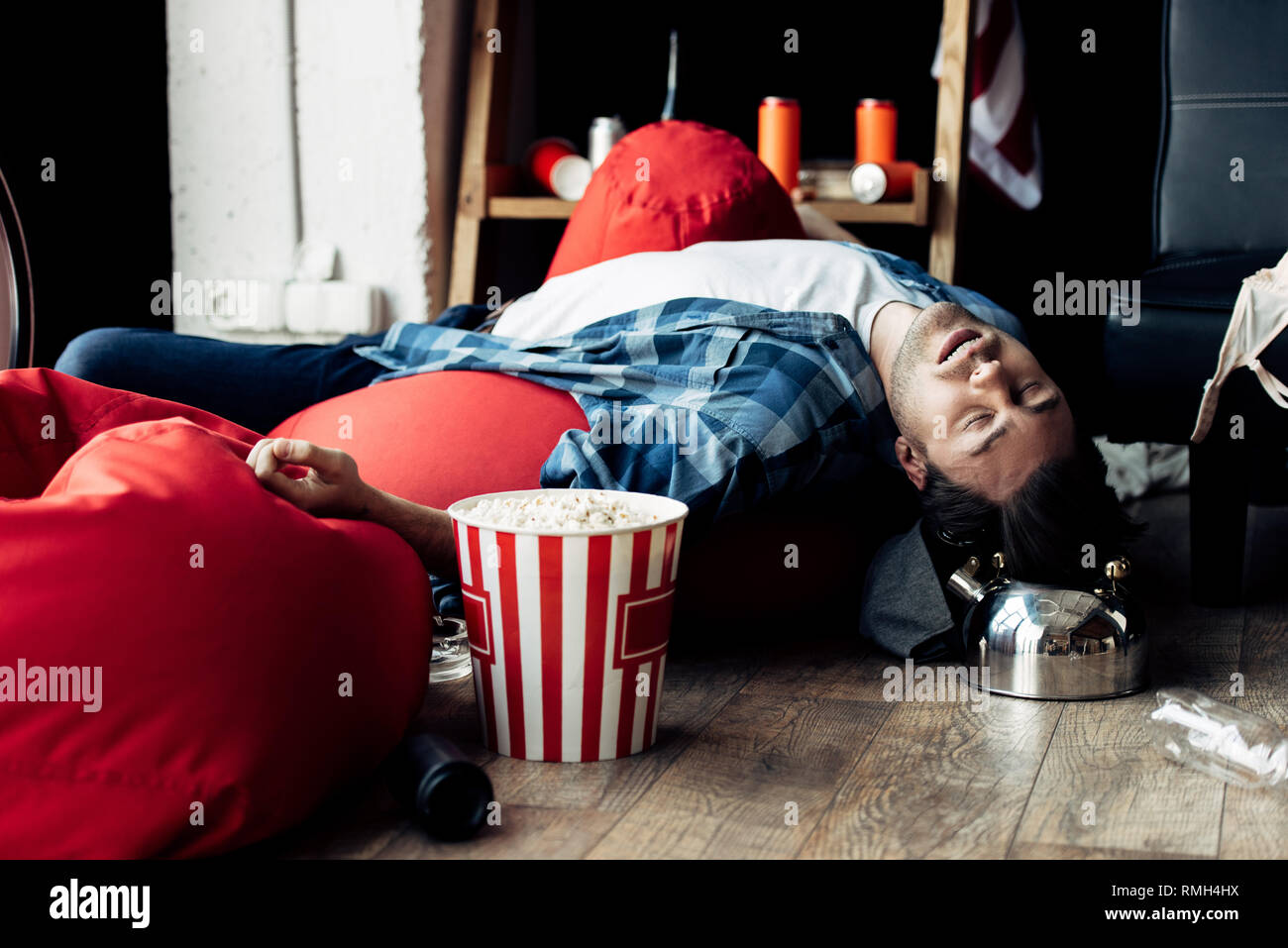 drunk man sleeping on bean bag near popcorn box after party Stock Photo ...