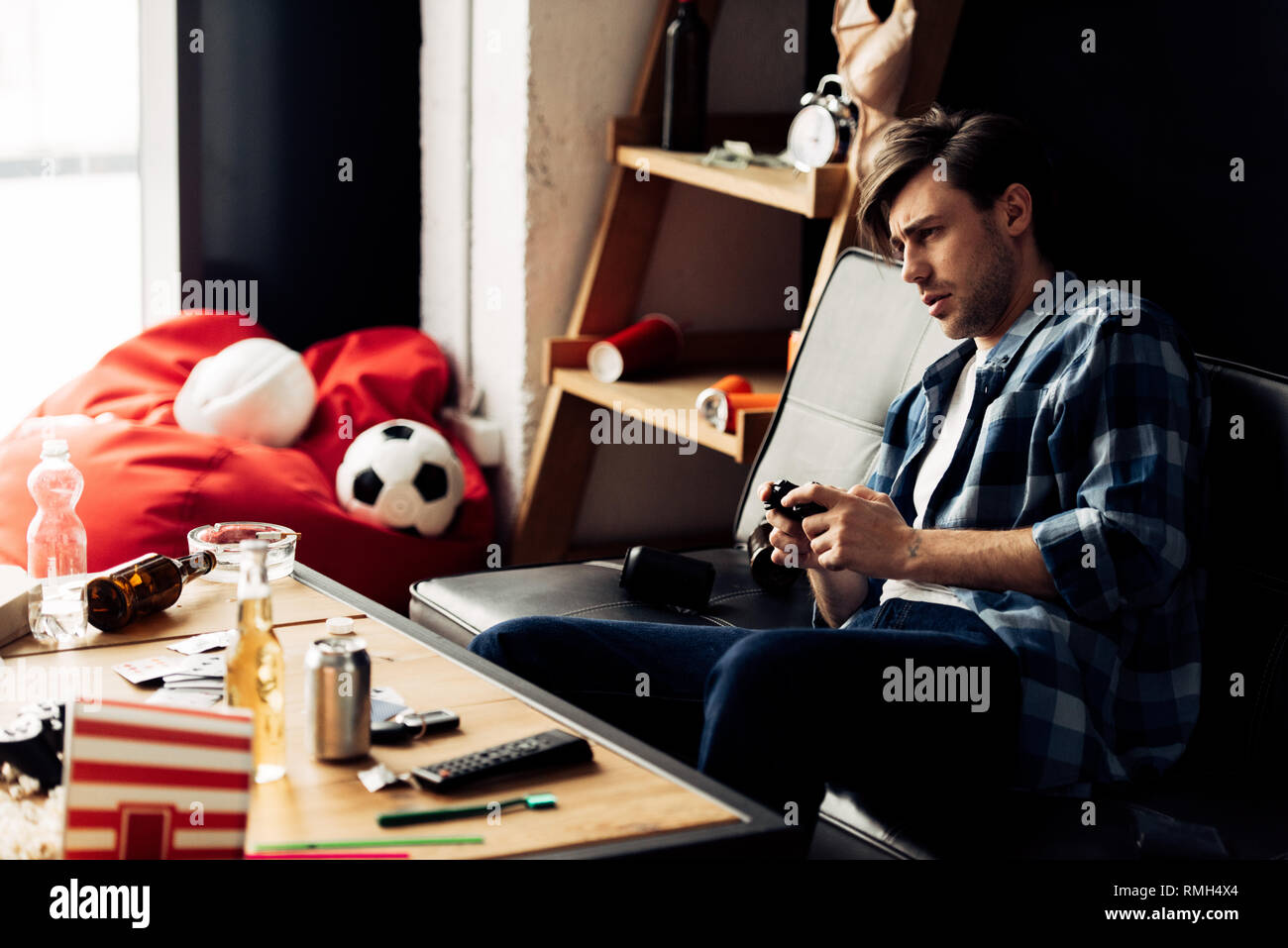 tired man playing video game in messy living room Stock Photo - Alamy