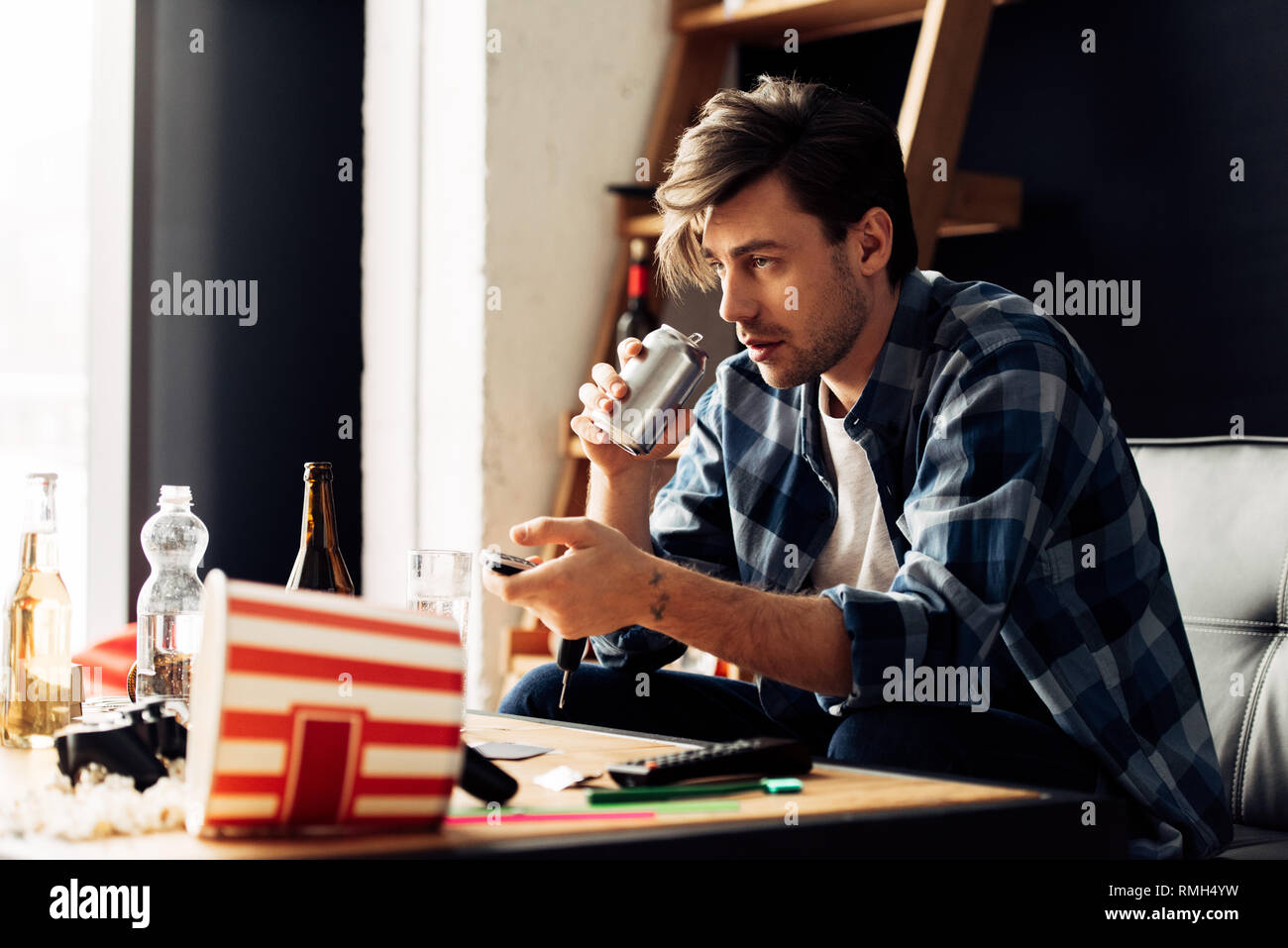 selective focus of drunk man holding remote control and watching tv ...