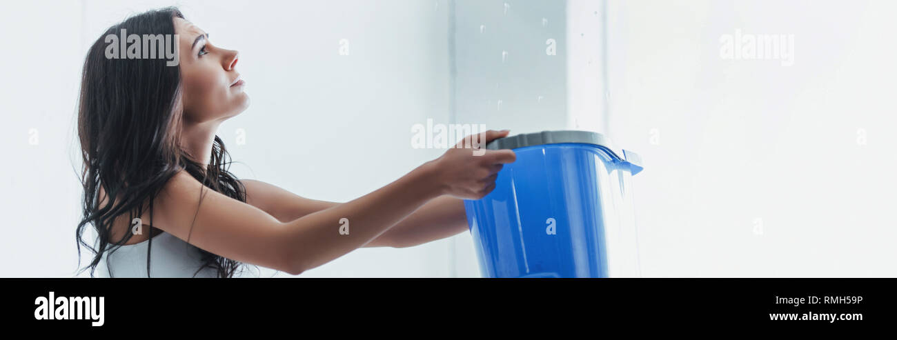 Worried young woman holding bucket under water drops Stock Photo - Alamy