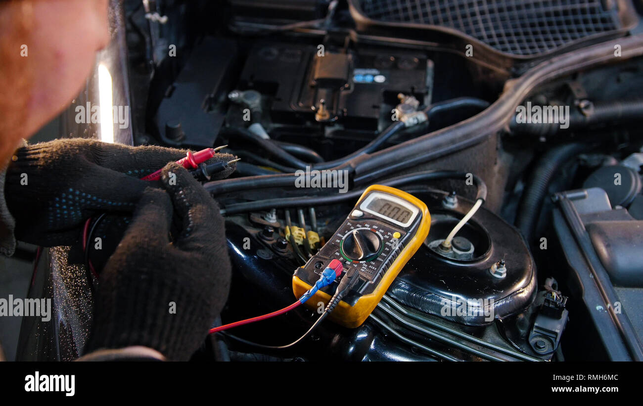 Car service. Mechanic man checks the voltage with a multimeter Stock ...