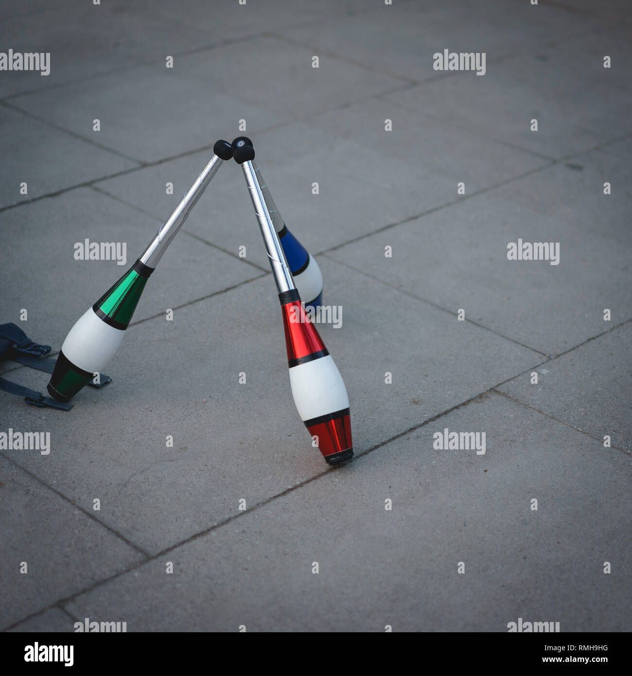 Three red, green and blue juggling clubs on a pavement. Square format ...
