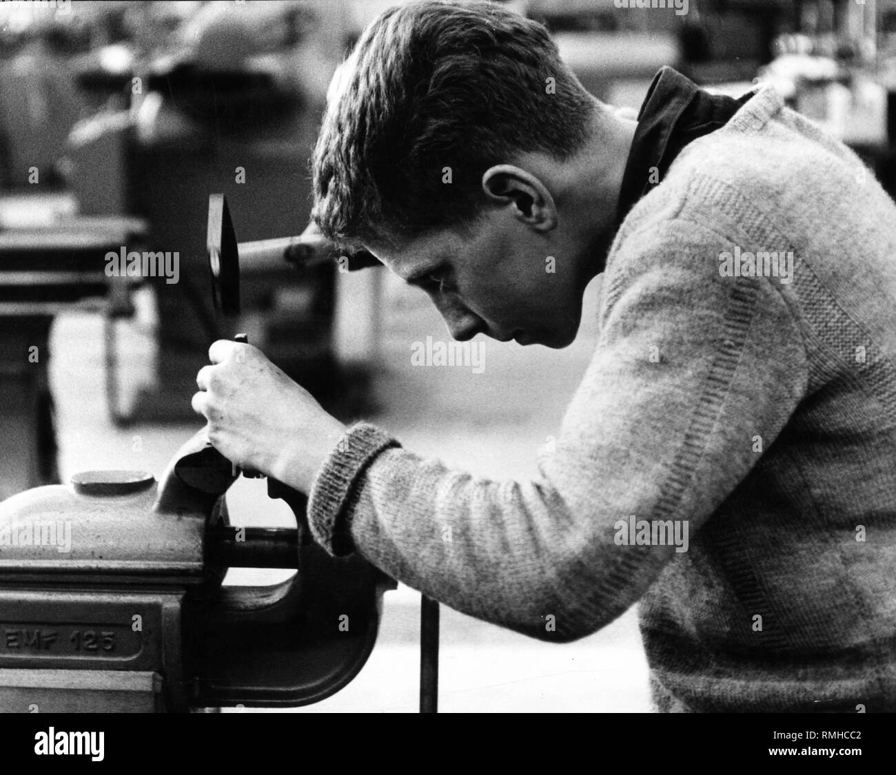 A young apprentice is working on a vise in a machine factory Stock ...